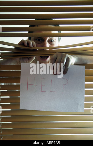 Man trapped behind window with help sign Stock Photo - Alamy