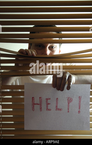 Man trapped behind window with help sign Stock Photo - Alamy