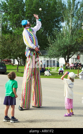 A man on stilts juggling entertaining two small children Stock Photo ...