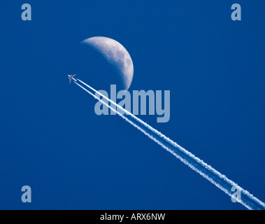 Jet airplane, its contrail and a crescent moon at sunset. The plane ...
