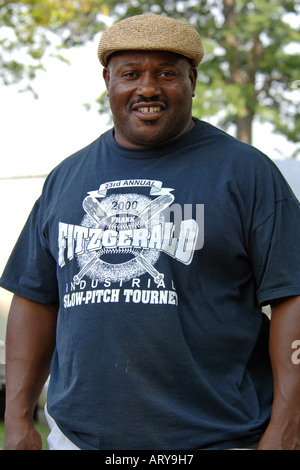 A rotund man wearing a flat cap and checked shirt under braces holds on ...