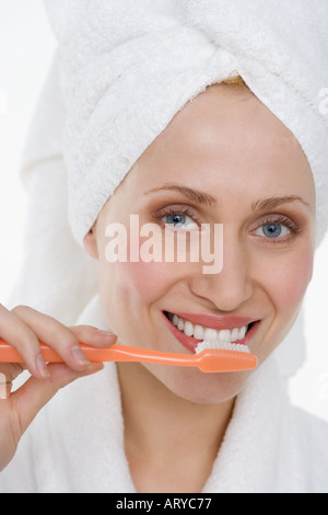 Smiling woman brushing her teeth with towel on her head. A great smile ...