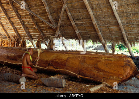 Hawaiian man wearing malo, carving contemporary Hawaiian sailing canoe ...