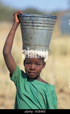 African village life. water chore. african girl carrying a basin of ...