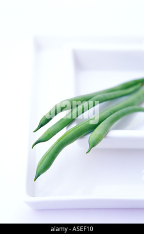 Green fresh string beans tantalisingly hanging over a set of square ...