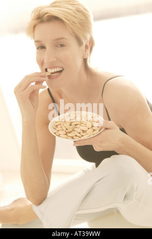 Woman eating almonds Stock Photo - Alamy