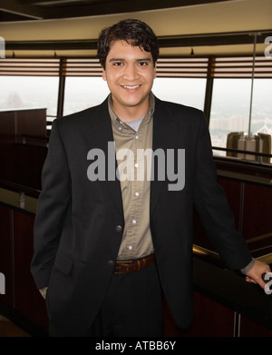 Portrait of smiling man standing in station with suitcase and smart ...