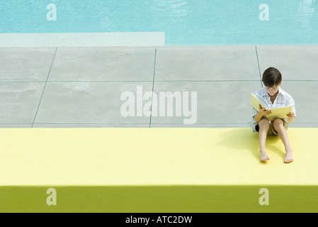 BOY READING BY POOL Stock Photo: 21663466 - Alamy