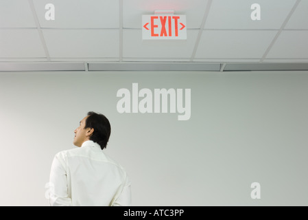 Man standing beneath exit sign with eyes closed Stock Photo - Alamy