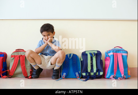 Sad boy crouching with hand on head against white background Stock ...