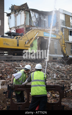 Construction workers dampen down dust with a water hose during the ...