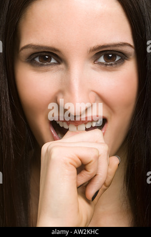 Pretty young woman biting her finger, portrait Stock Photo - Alamy