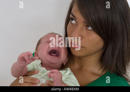 distraught young mother or childminder holding crying baby Stock Photo ...
