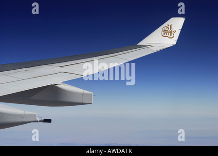 Wing of a flying Airbus 330-200 of the airline "Emirates" and blue sky ...