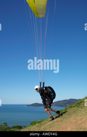 Taking off hobby paraglider pilot on a mountain slope with professional ...