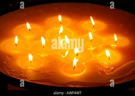 Large candle with multiple burning wicks Stock Photo - Alamy