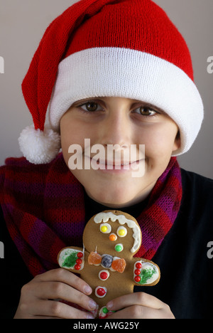 The boy is holding a gingerbread cookie in the shape of a snowman ...