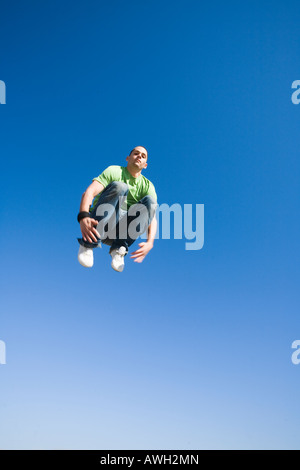 Young man jumping trough the sky with legs spread Stock Photo - Alamy