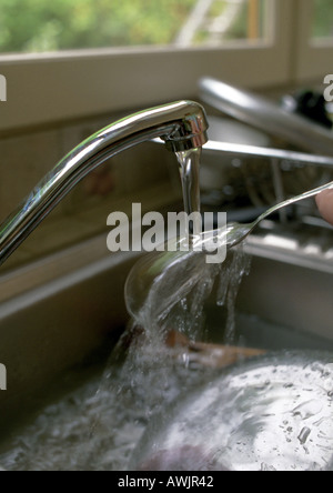 Water flowing from kitchen faucet. Water conservation, shortage and ...