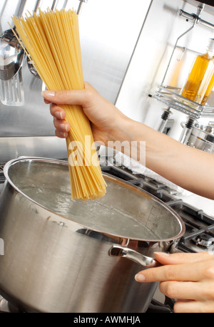 Female hand holding uncooked spaghetti above ingredients on a table ...