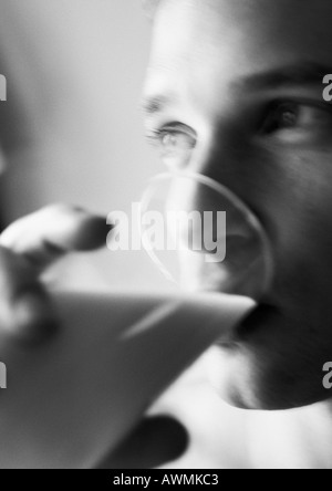 partial view of blurred man with glass of cappuccino holding smartphone ...