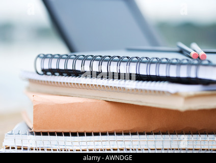 Laptop, stack of books, notebook, pencils in office background for ...