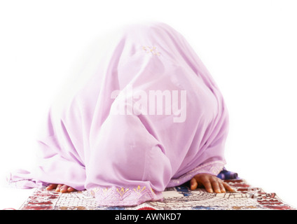 Muslim woman kneeling on the floor reciting Islamic prayers at home ...