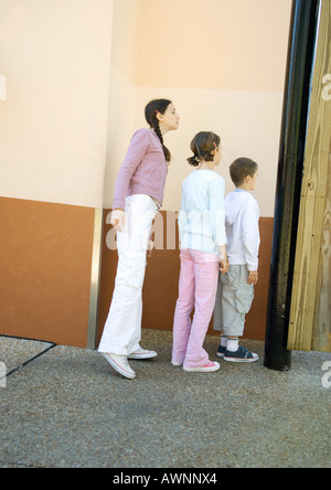 Preteen girl looking around corner of wall, cropped Stock Photo - Alamy