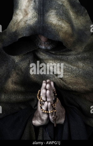 Hooded monk wearing cloak, praying Stock Photo - Alamy
