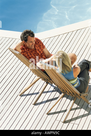 Deck chairs next to swimming pool with blue water Stock Photo - Alamy