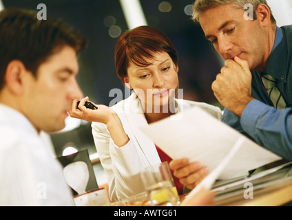 Young business people looking at documents and products standing at the ...