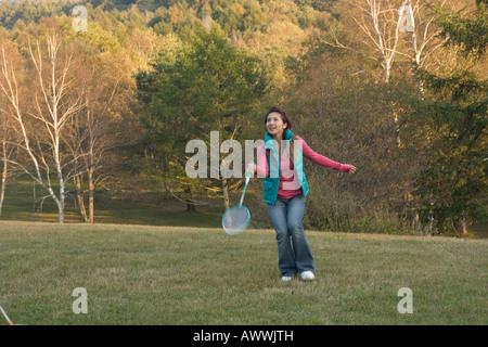 Active woman playing badminton in a green meadow wearing a bright ...