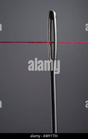 red thread through needle eye and red button with multi colored thread ...