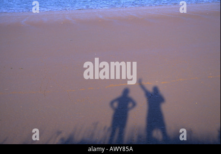 Two people cast shadows on sandy beach Stock Photo - Alamy