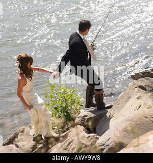 bride in dress with fishing rod sitting by a lake trying to catch a ...