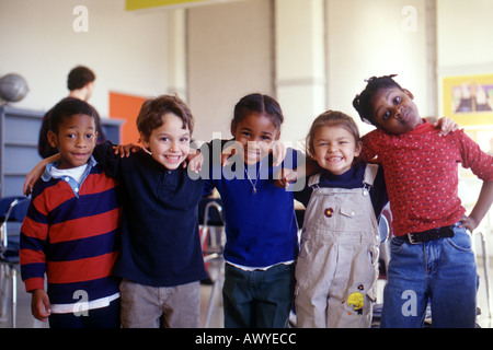 Five multi cultural first graders in classroom smile for the camera ...