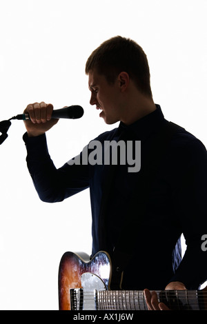 Silhouette of singing young man with microphone on white background ...