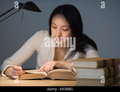 Asian women reading book at desk with laptop computer for professional ...