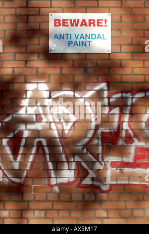 Beware Anti Vandal Paint sign on a graffitied brick wall Stock Photo ...