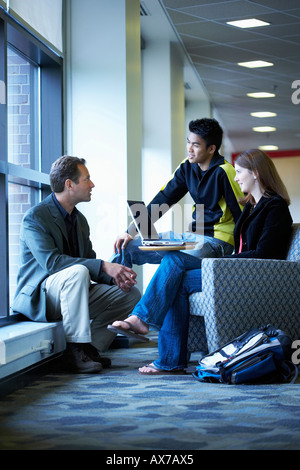 Side profile of a professor and two college students smiling in a ...