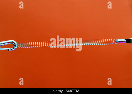 Steel spring is stretched between two hooks stress Stock Photo - Alamy
