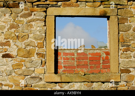 A stone wall with a window frame shows the sky, with broken glass and ...