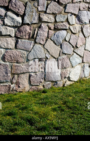 A stone wall made of irregularly shaped gray and brown stones held ...