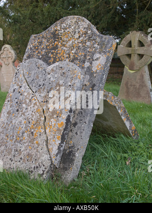 An old 19th century leaning gravestone cross at cemetery, blurred ...