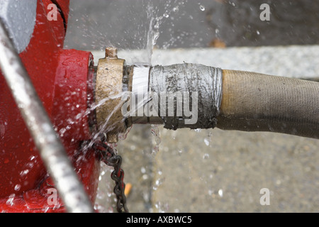 Leaking red fire hydrant and fire hose attached Stock Photo - Alamy