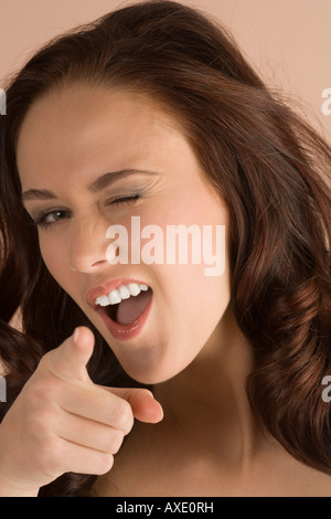 winking woman portrait point fingers on copy space yellow background ...