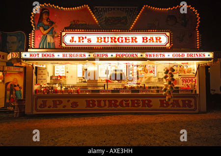 Candy floss and Chips sign at food stall in funfair with ride behind ...