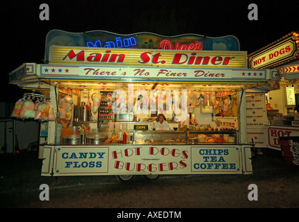 Candy floss and Chips sign at food stall in funfair with ride behind ...
