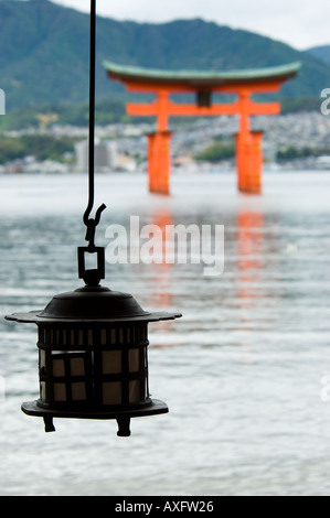 The floating torii gate of Miyajima is reflected in the water at high ...