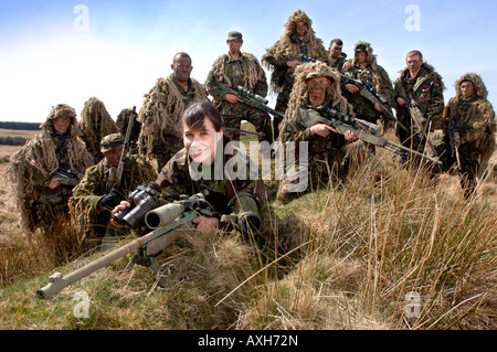 Camouflaged woman sniper in ghillie suit posing with rifle in foggy night. Special Weapons and ...